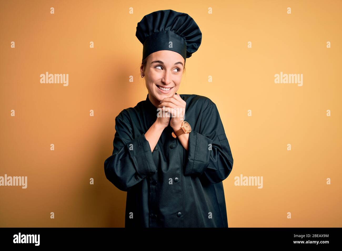 Young beautiful chef woman wearing cooker uniform and hat standing over ...