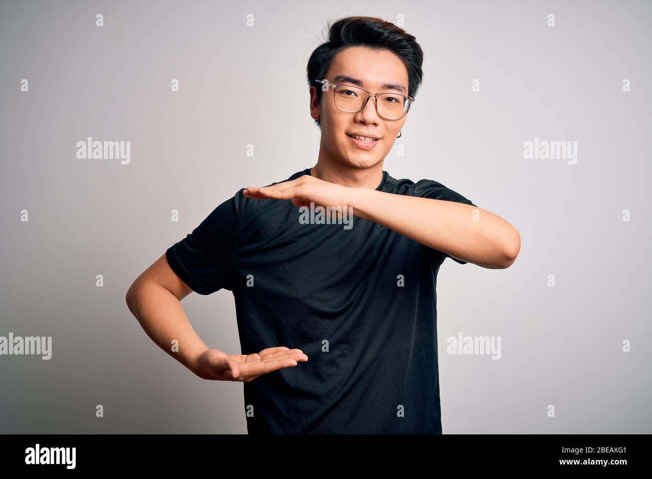 Young handsome chinese man wearing black t-shirt and glasses over white ...