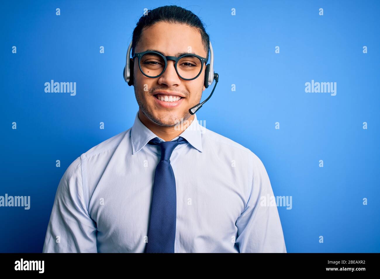 Young brazilian call center agent man wearing glasses and tie working ...