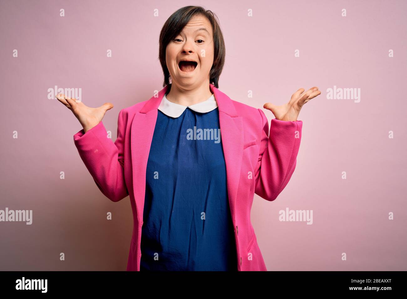 Young down syndrome business woman over pink background celebrating ...