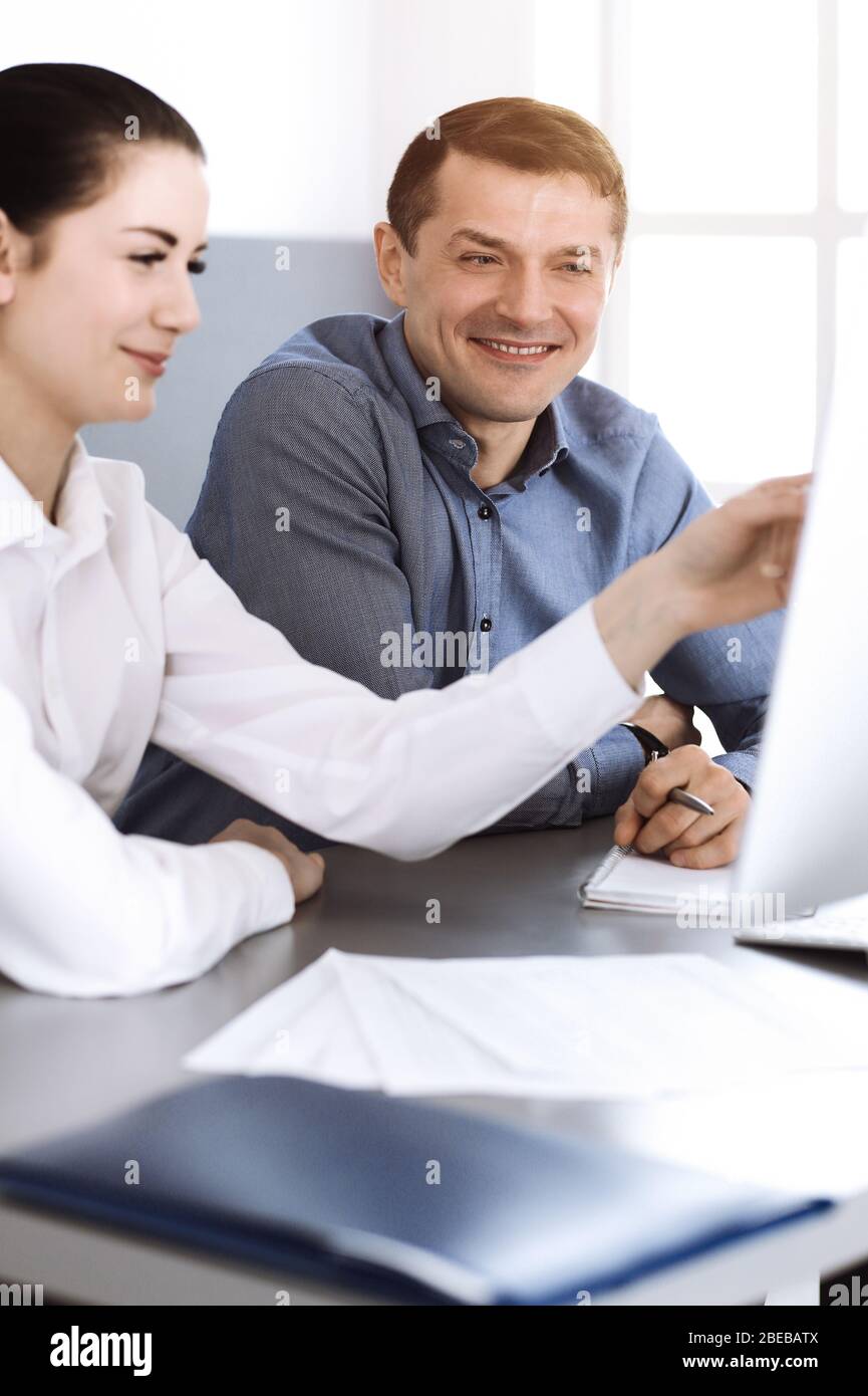 Friendly smiling businessman and woman working with computer in modern office. Headshot at ...