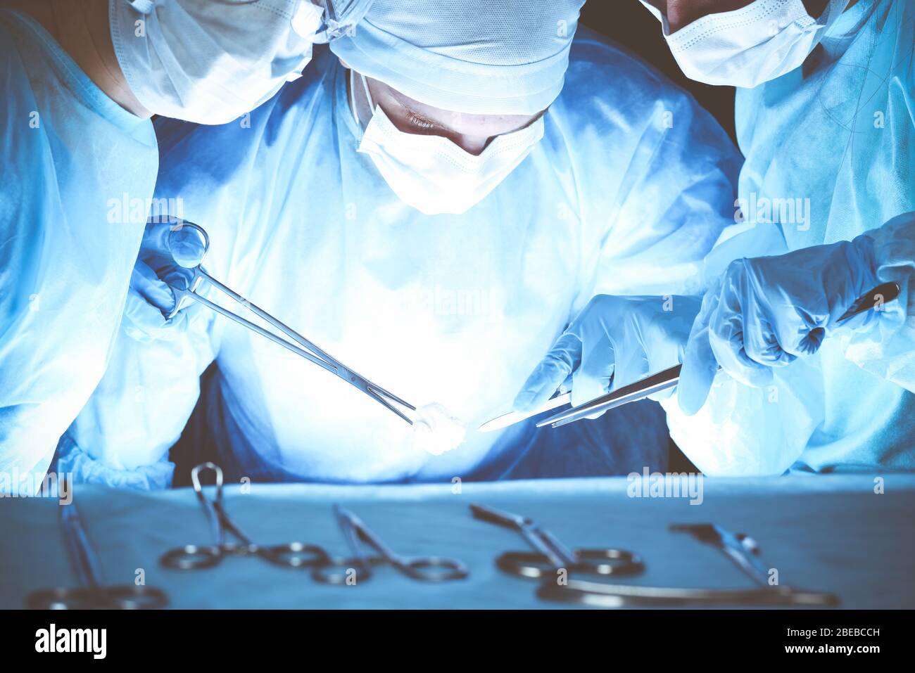 Group of surgeons wearing safety masks performing operation. Medicine ...