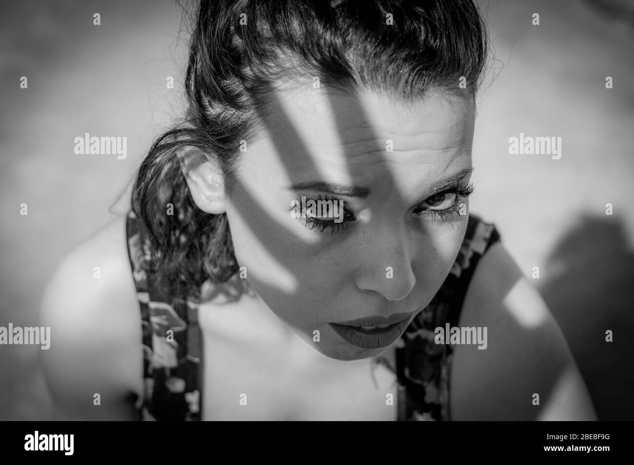 Young woman with a hands shadow on the face. Violence, menace and fear ...