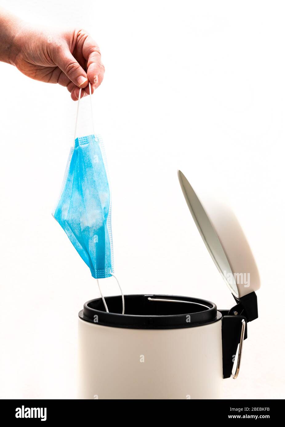 Hand throwing away a protective face mask to the garbage trash can. End ...