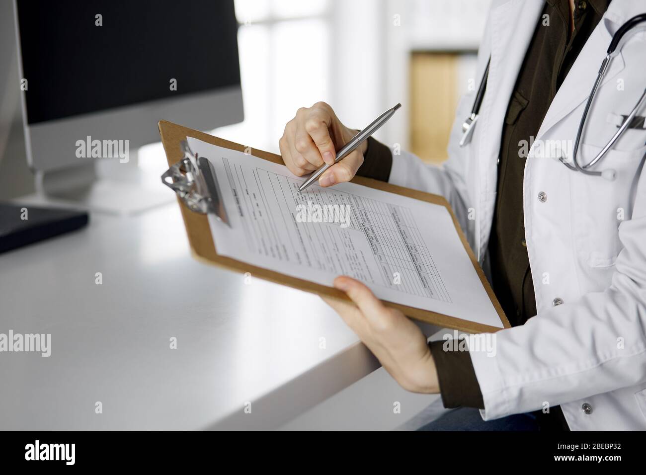 Unknown female doctor using clipboard in clinic. Perfect medical service in hospital. Medicine ...