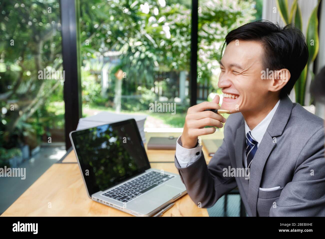 Young businessman laughing with a colleague while sitting on a chair in ...