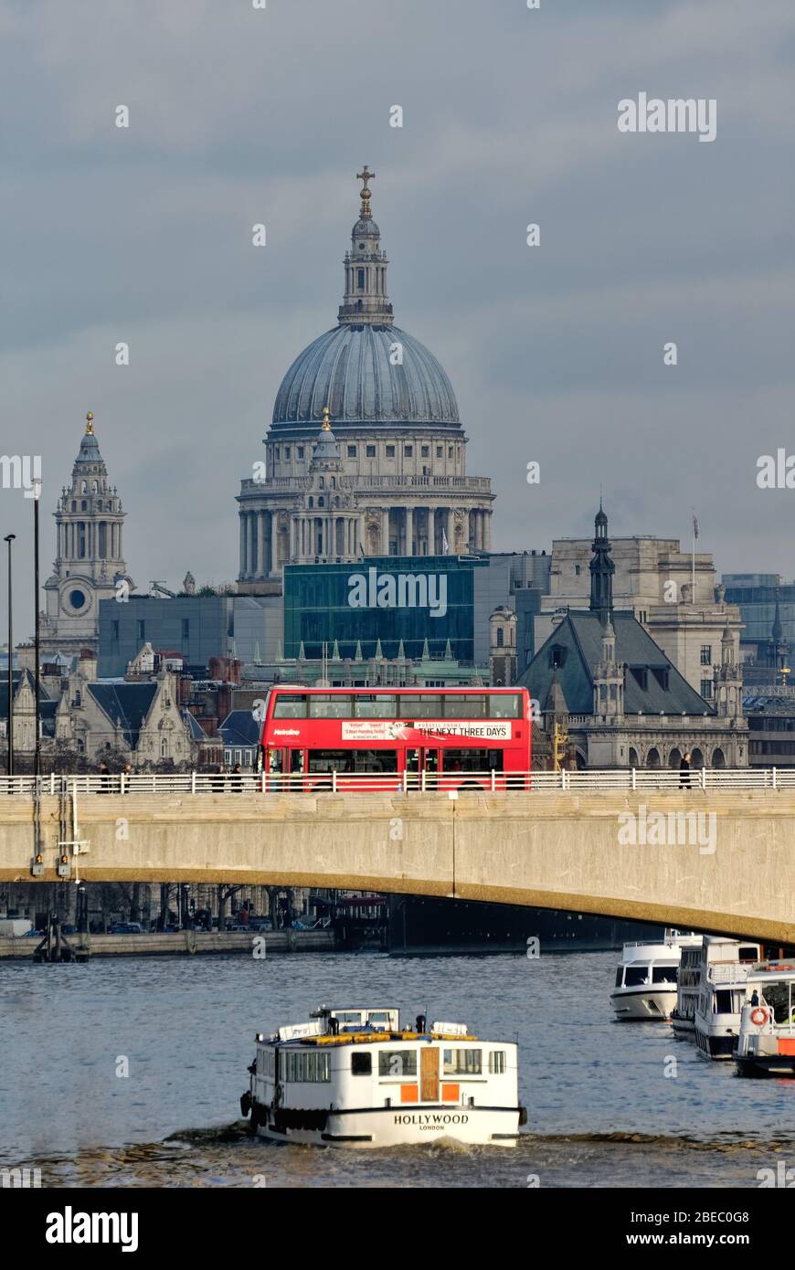 A red London bus passing over Waterloo bridge with St.Paul's cathedral ...