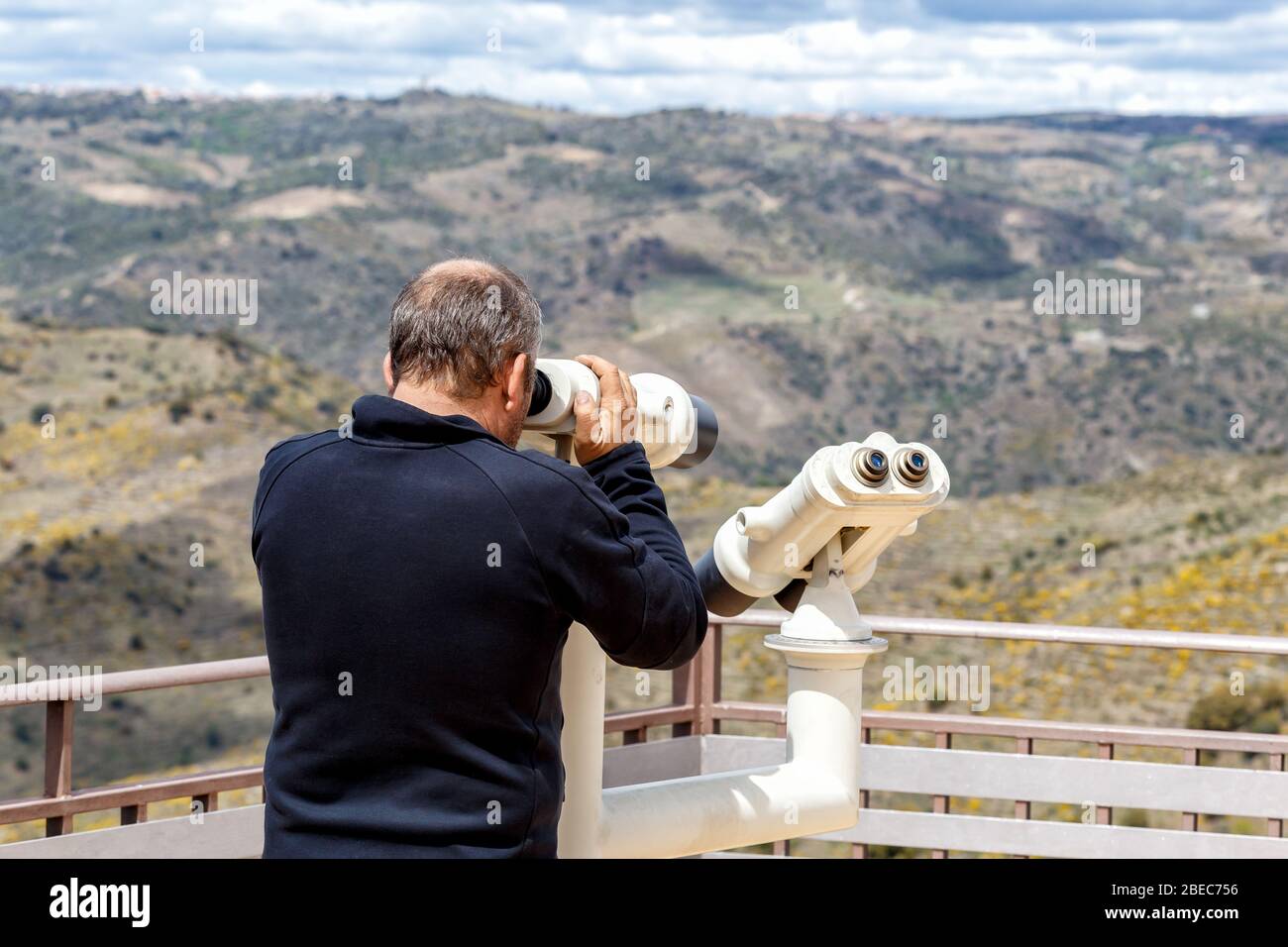 Man looking through high powered binoculars on a scenic mountain ...