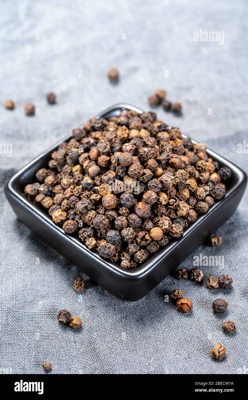 Bowl with dried black round peppers condiment close up Stock Photo - Alamy