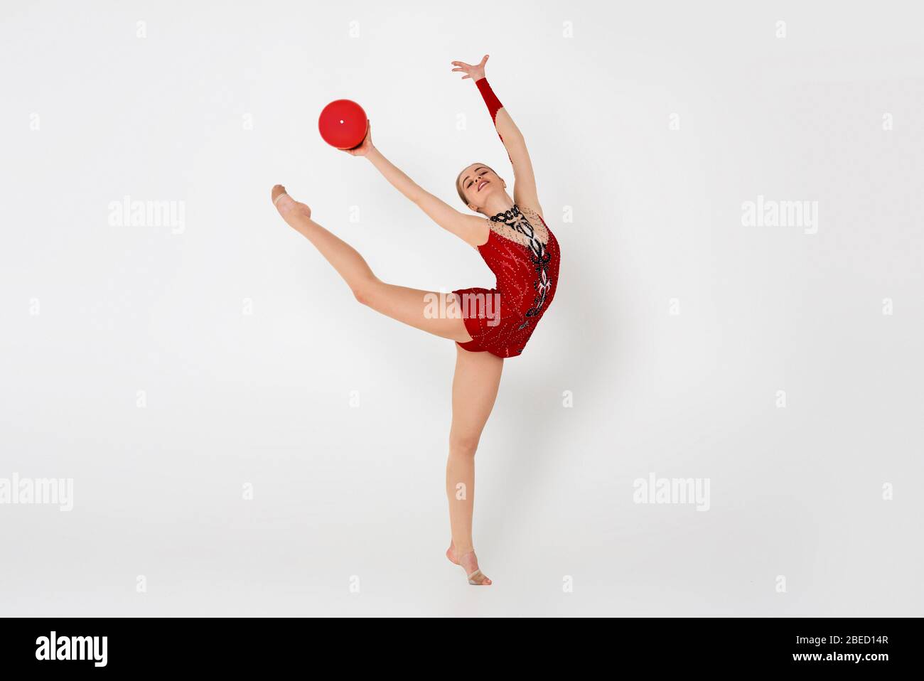 Young beautiful sportswoman doing rhythmic gymnastics with ball, white ...