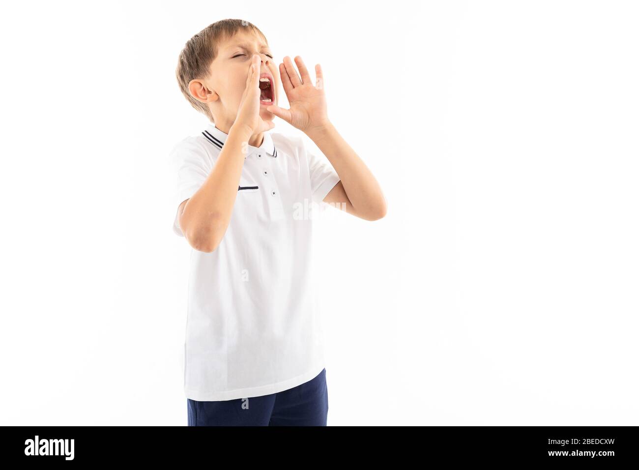 cute boy with bangs in a white t-shirt screaming on a white background ...