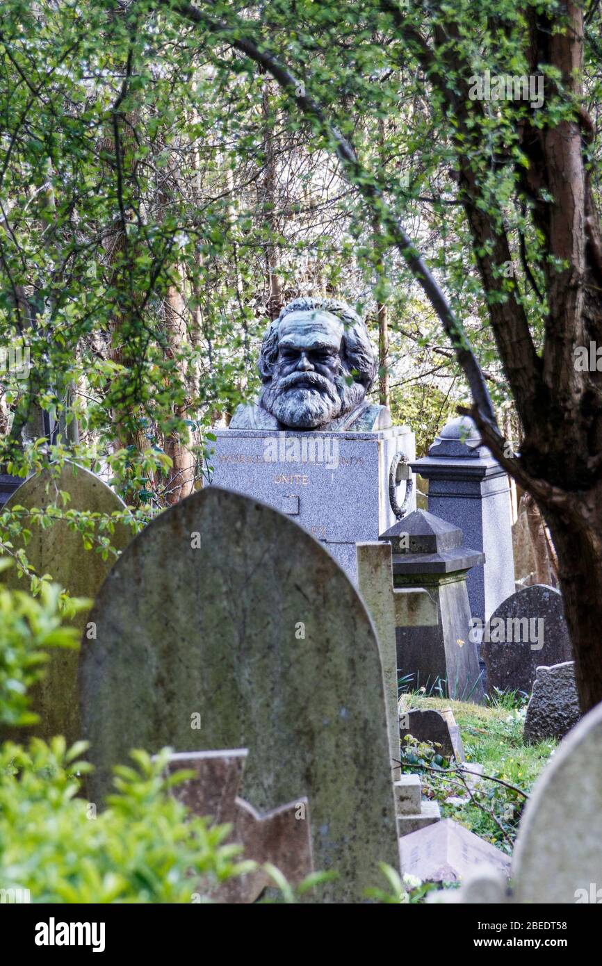 The bust of Karl Marx looks out through the gravestones and foliage ...