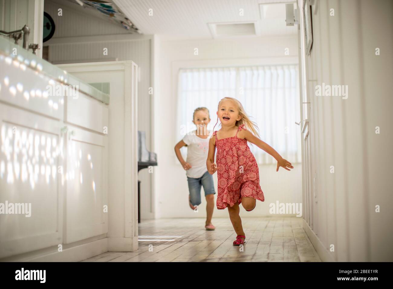 Two little girls have fun running through the house together Stock ...