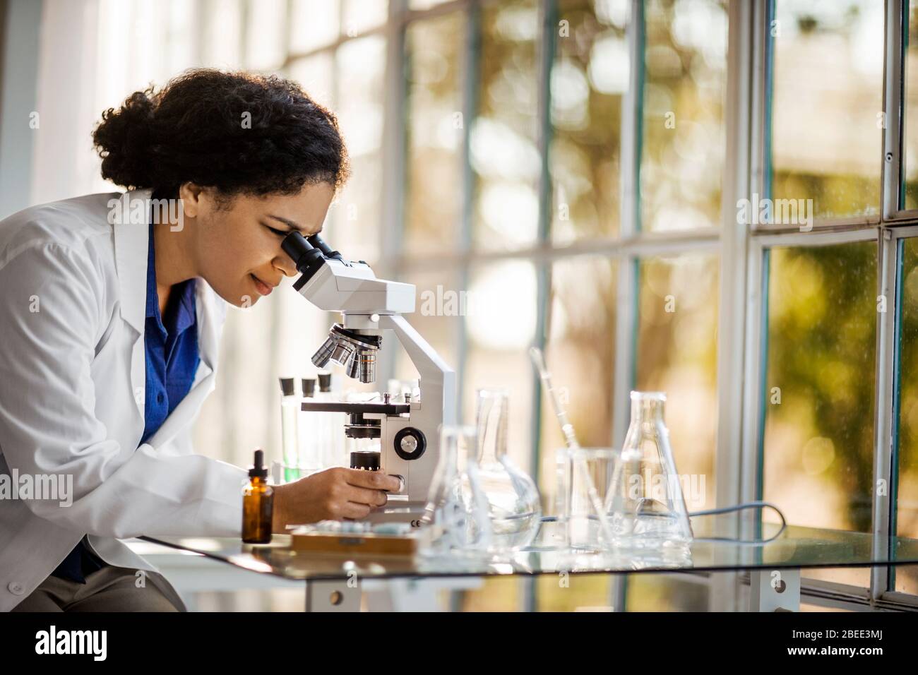 Scientist looking through a microscope at a sample Stock Photo - Alamy