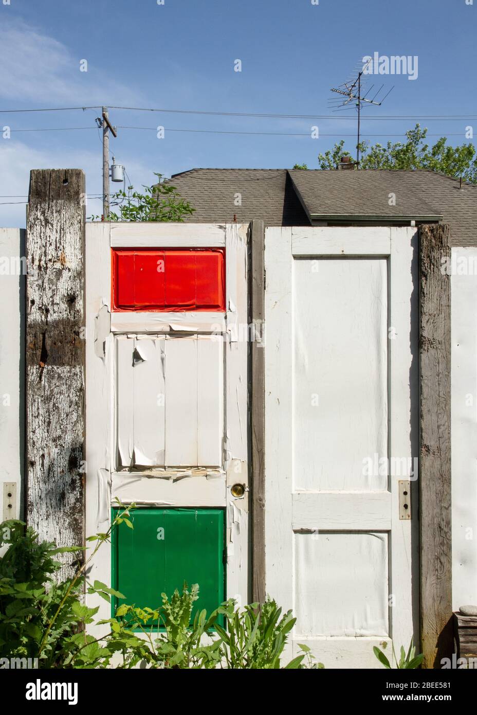 red, green and white garden door made of wood, embedded in run down ...