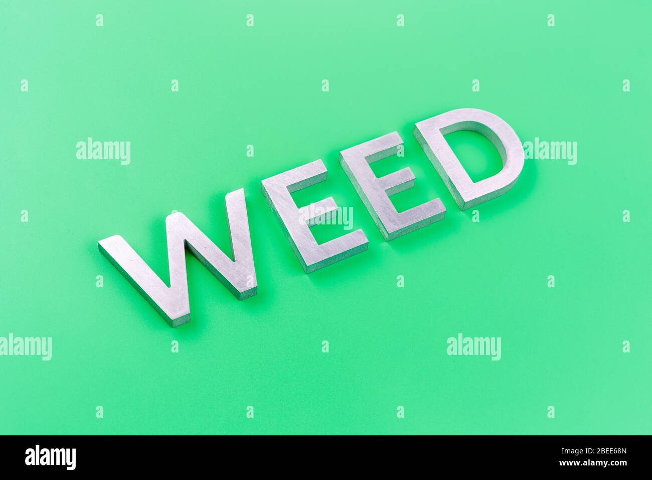 the word weed laid with silver metal letters on pastel green background ...