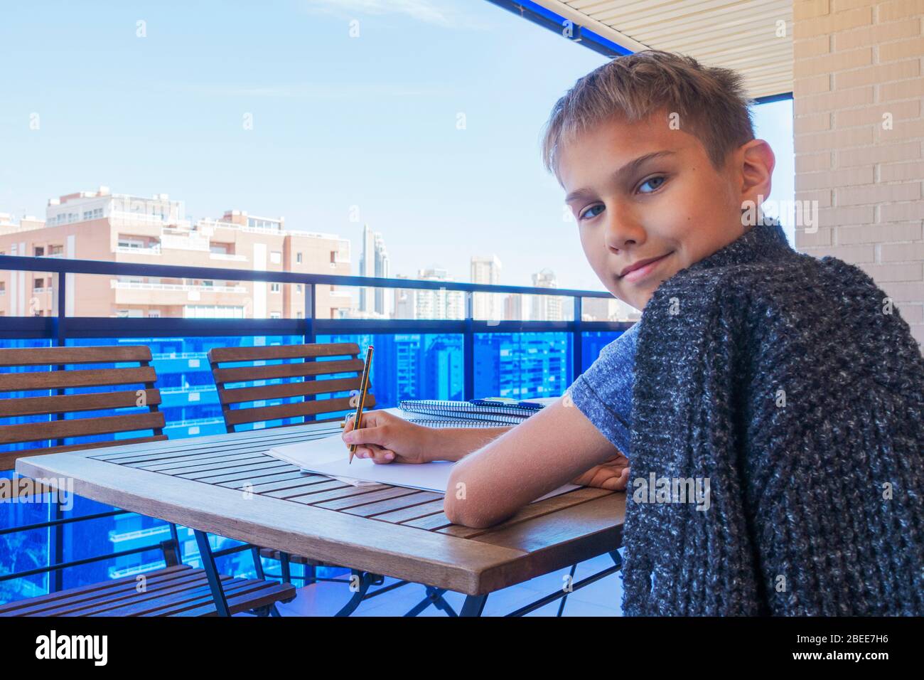 Child writing, doing homework in balcony. School, online learning ...