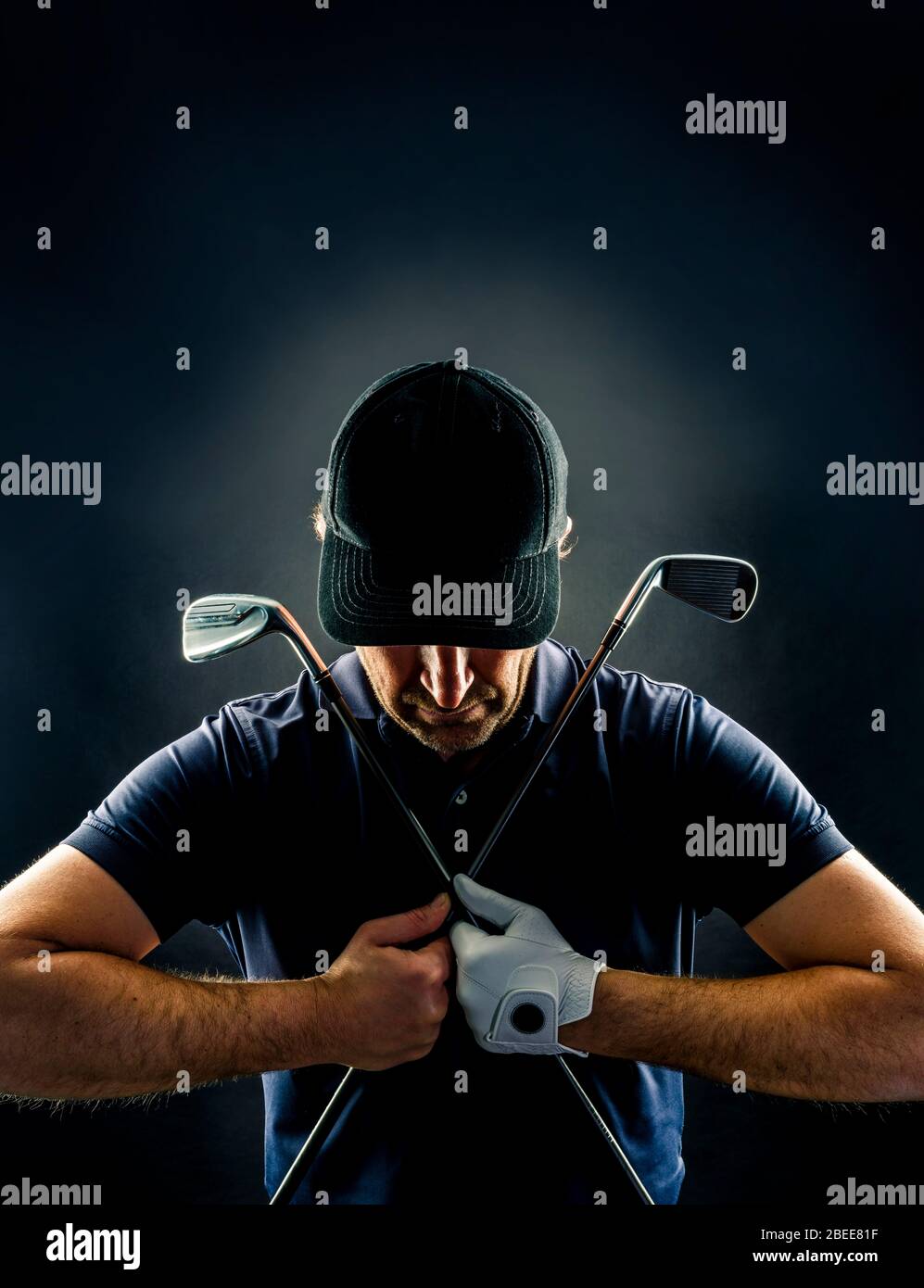 Close-up of a golf player with golf irons crossed on his chest ...