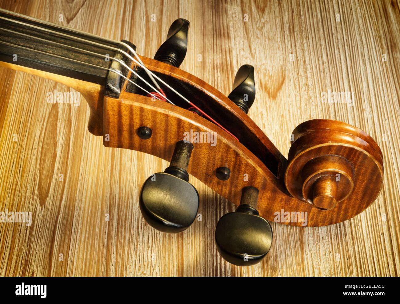 Neck and headstock of a cello with a textured wooden background and ...