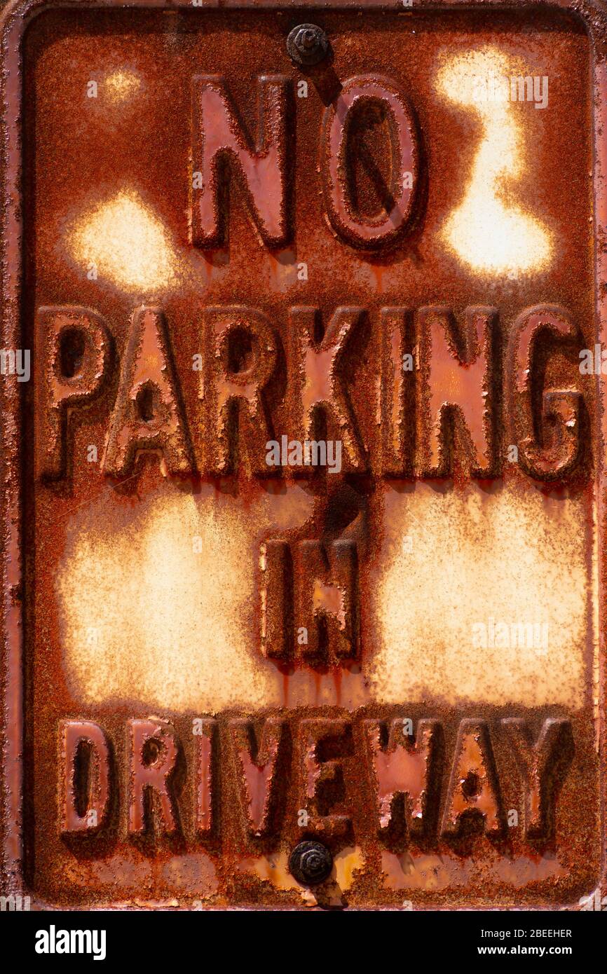 Rusted No Parking In Driveway street sign with blue skies in the ...