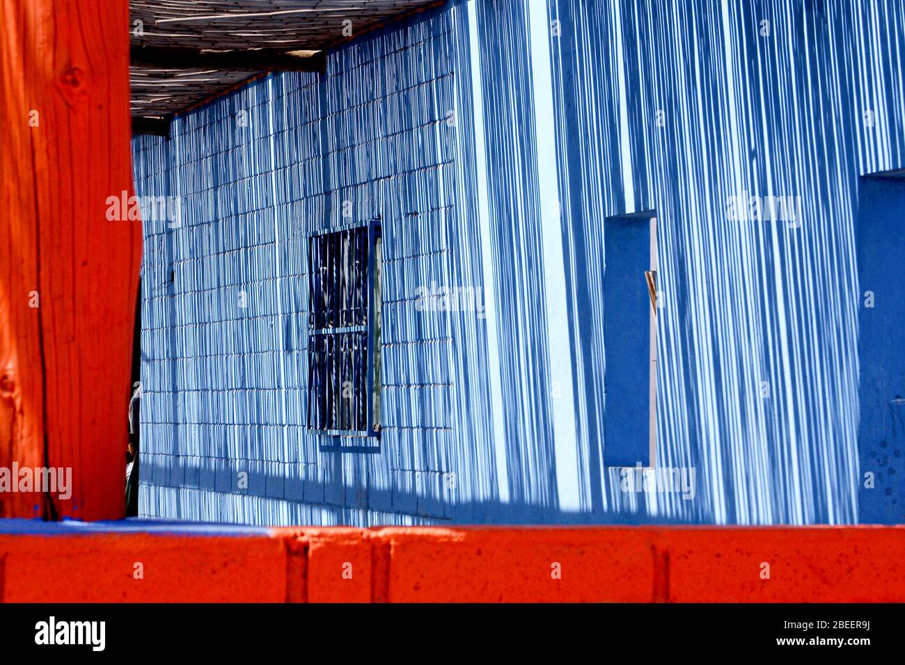 Dark shadows are cast on a brilliant blue wall to create patterns and ...