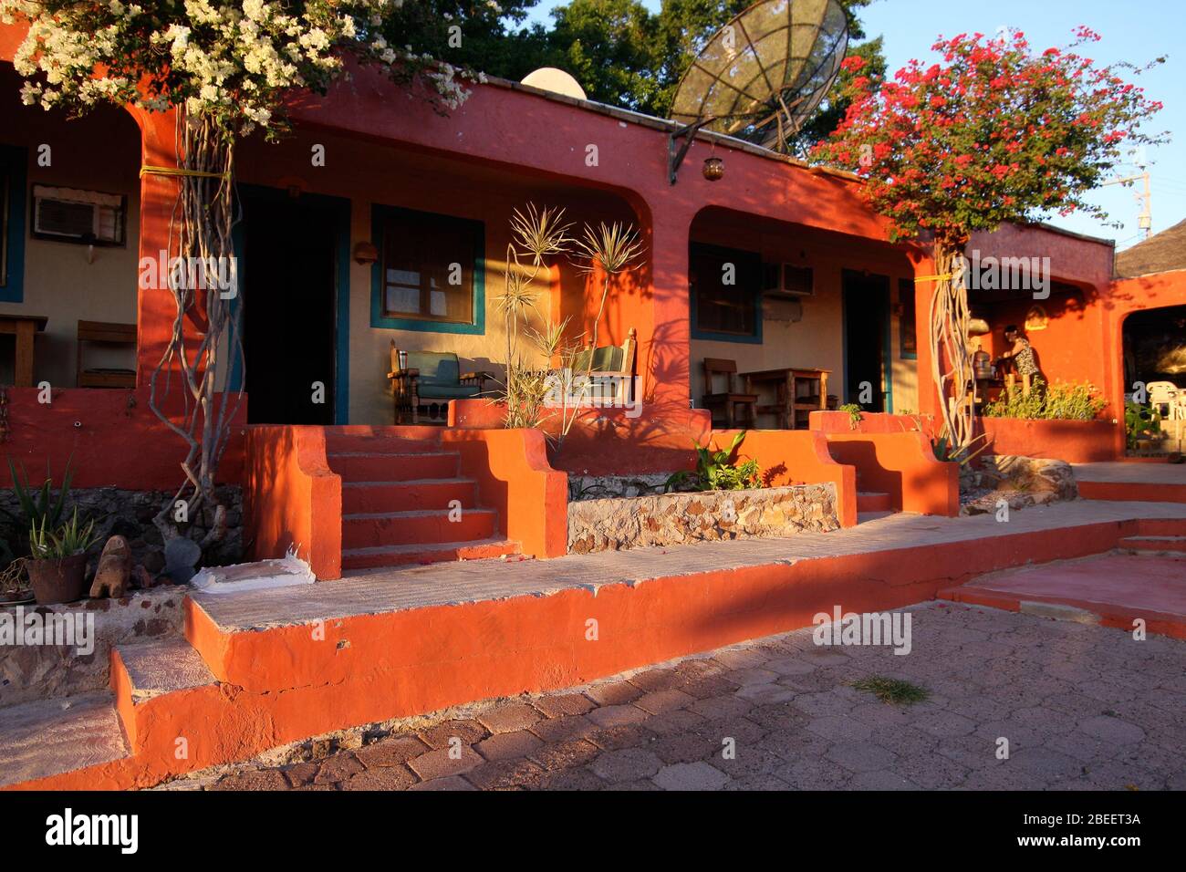The late afternoon sun lights up the front of a single story hotel and ...