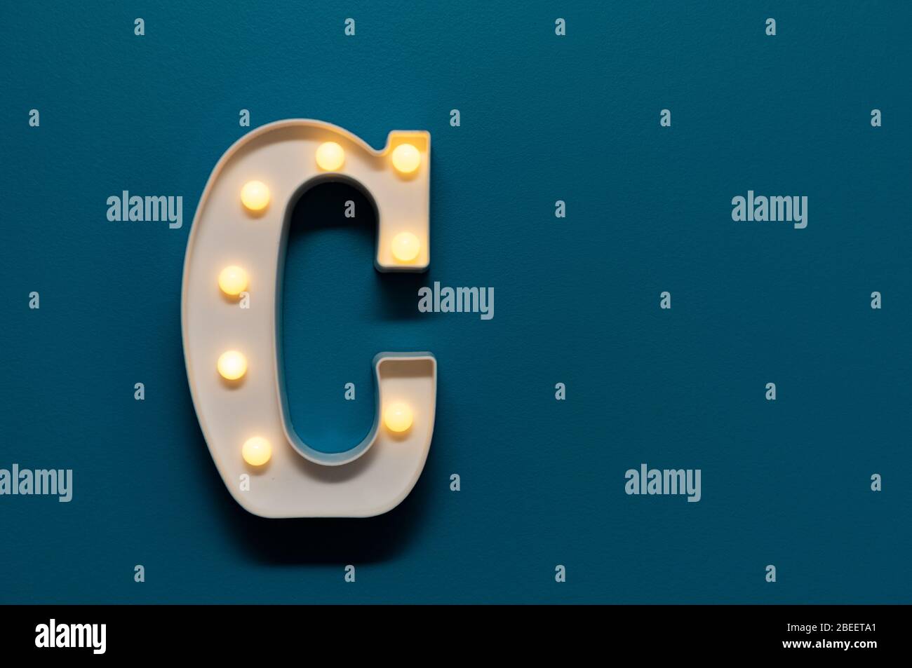 Single Light up Letter "C" on Teal wall, conceptual Stock Photo - Alamy