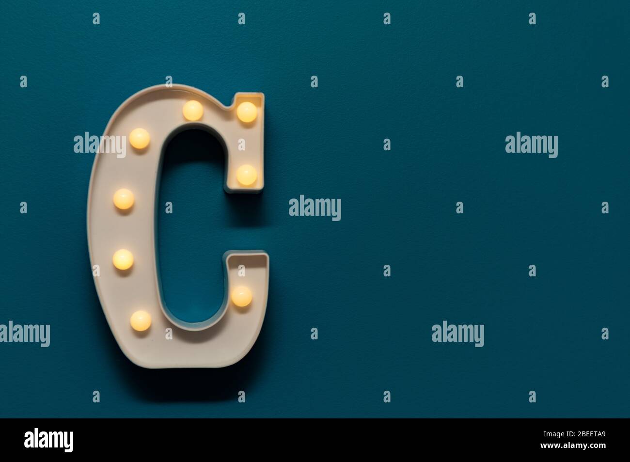 Single Light up Letter "C" on Teal wall, conceptual Stock Photo - Alamy
