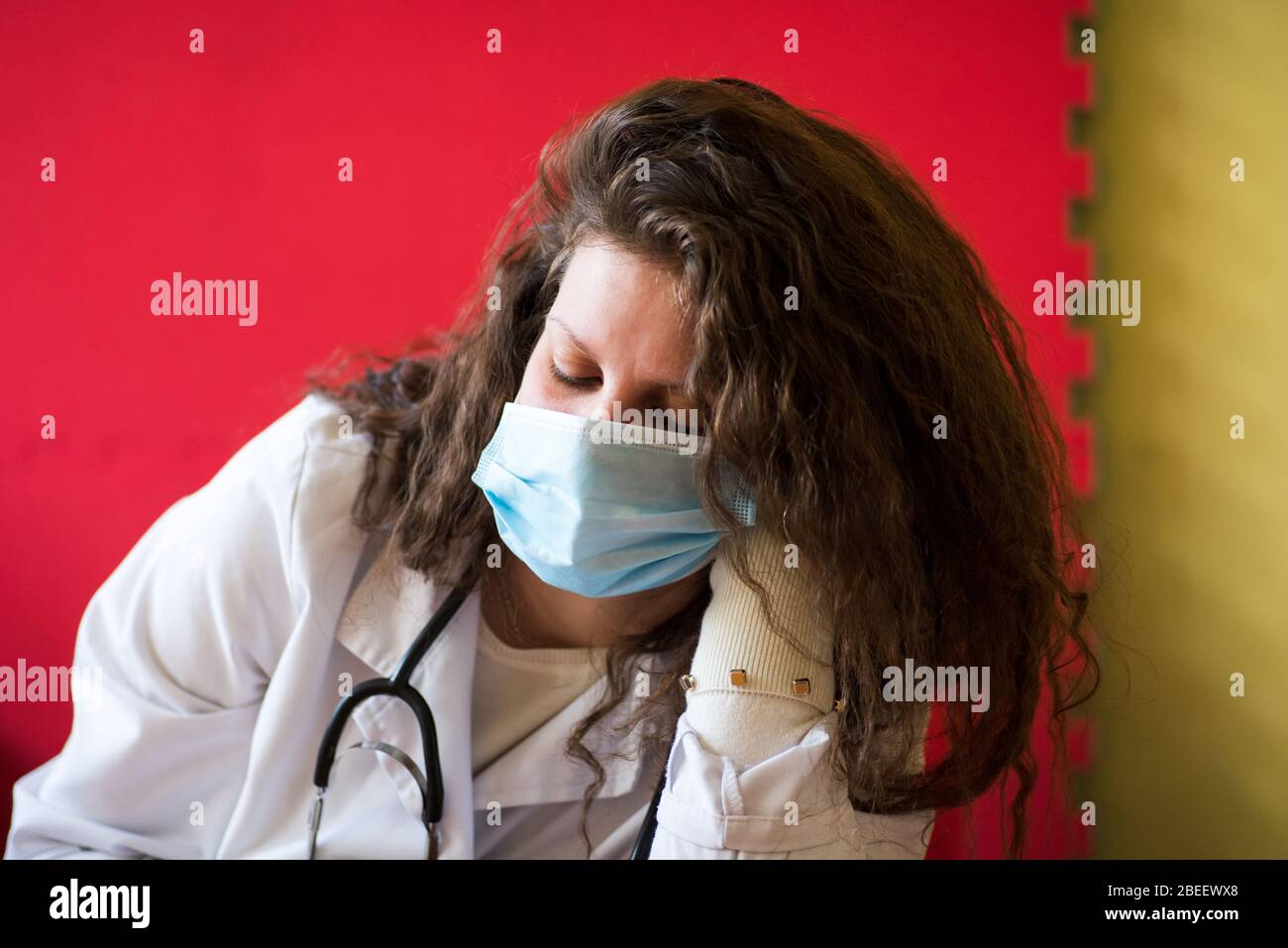 Tired female doctor taking nap on a table wearing mask close-up ...