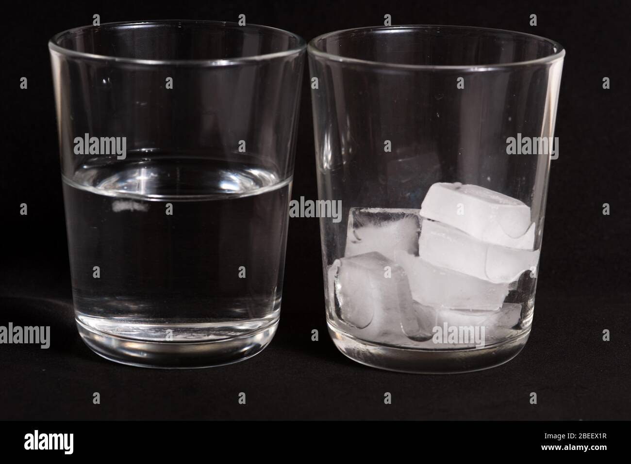 Melting ice concept with one glass filled with ice and another filled ...