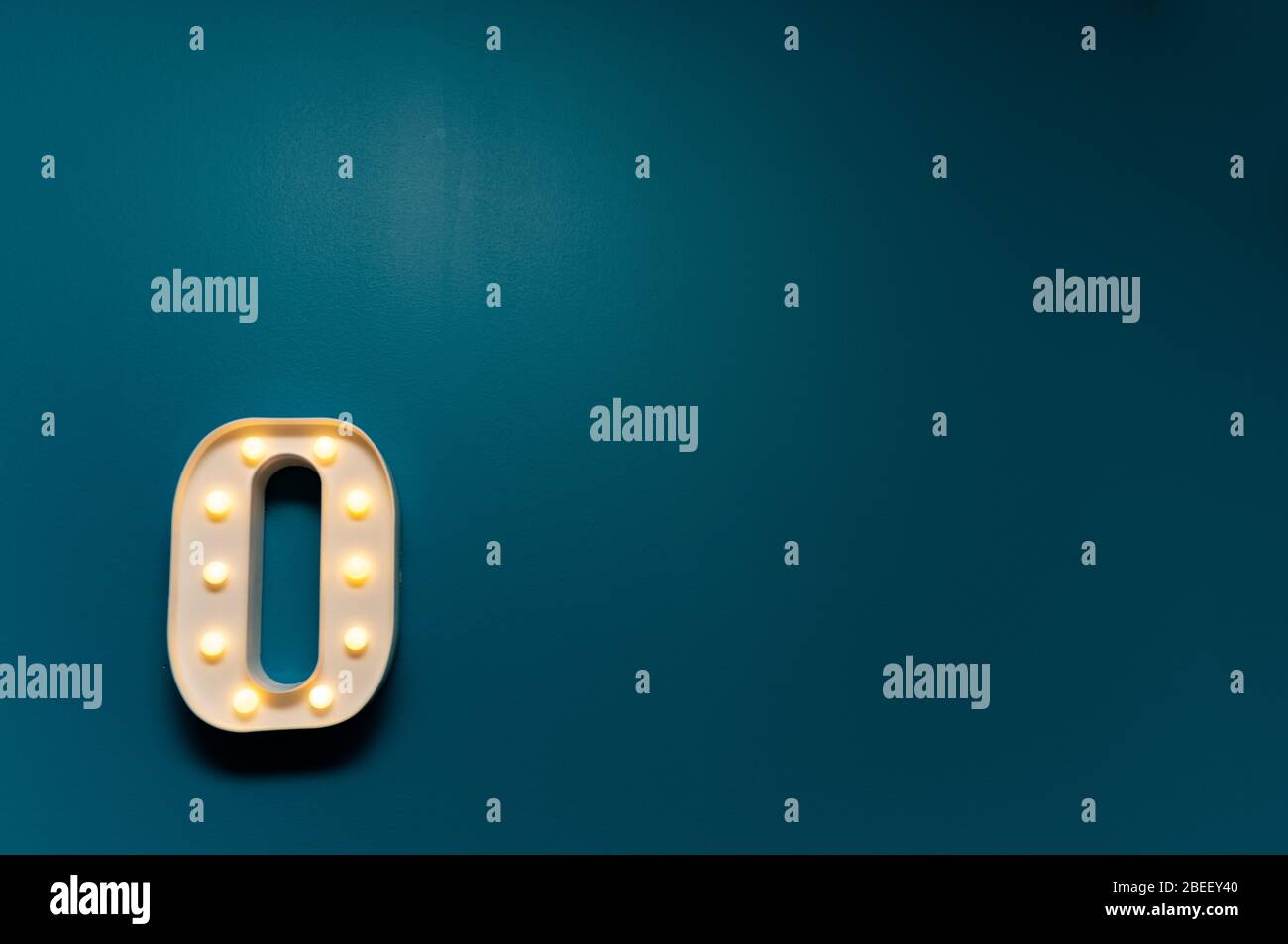 Single Light up Letter "O" on Teal wall, conceptual Stock Photo - Alamy