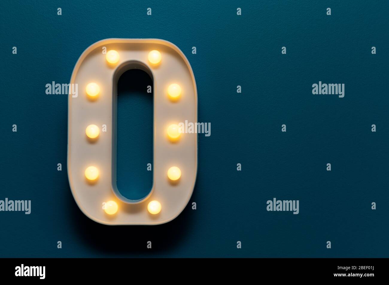 Single Light up Letter "O" on Teal wall, conceptual Stock Photo - Alamy