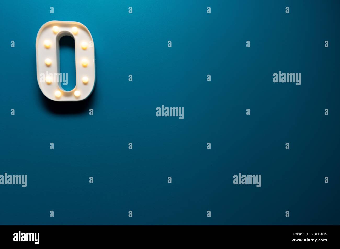 Single Light up Letter "O" on Teal wall, conceptual Stock Photo - Alamy