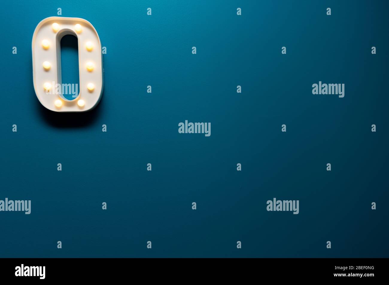 Single Light up Letter "O" on Teal wall, conceptual Stock Photo - Alamy