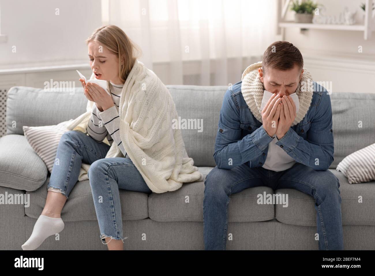 Infected man and woman coughing at home interior Stock Photo - Alamy
