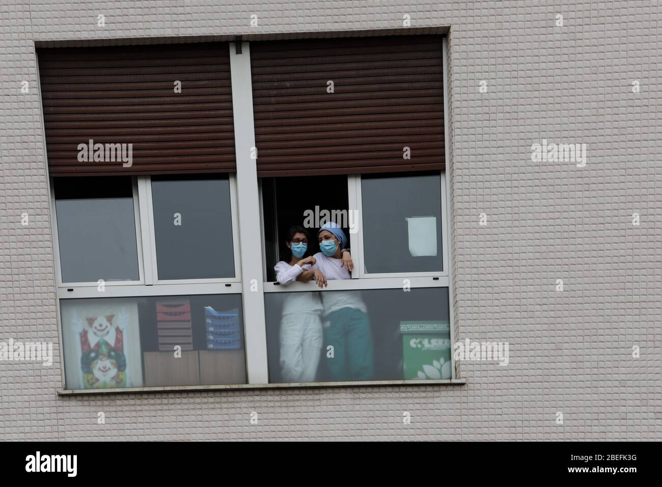 Two nurses look out the window of the Buzzi hospital during a moment of ...