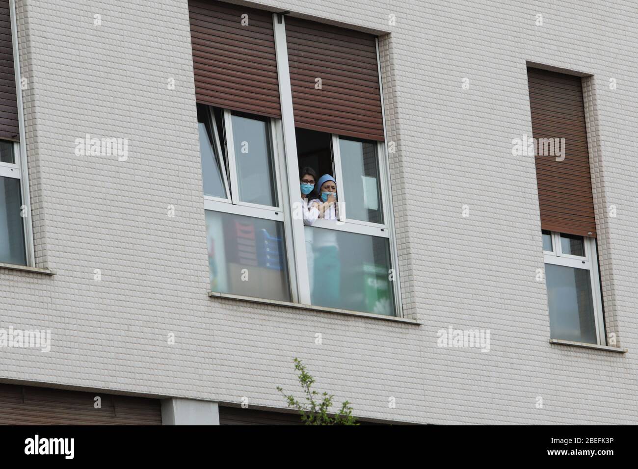 Two nurses look out the window of the Buzzi hospital during a moment of ...