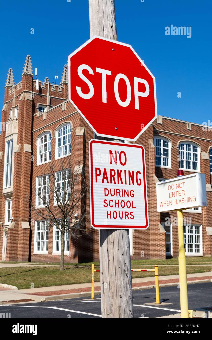 No Parking During School Hours and Stop sign with school building in ...