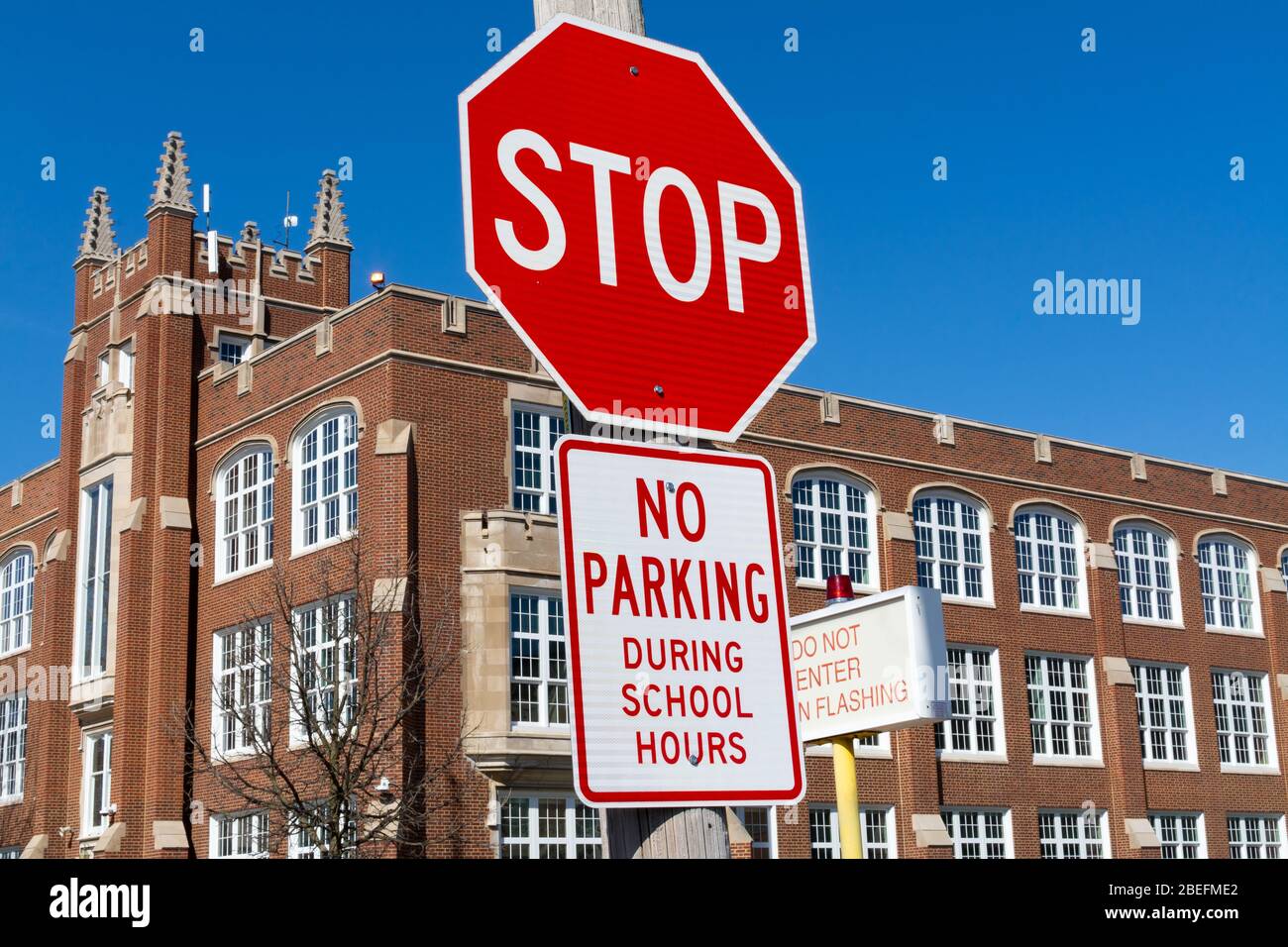 No Parking During School Hours and Stop sign with school building in ...