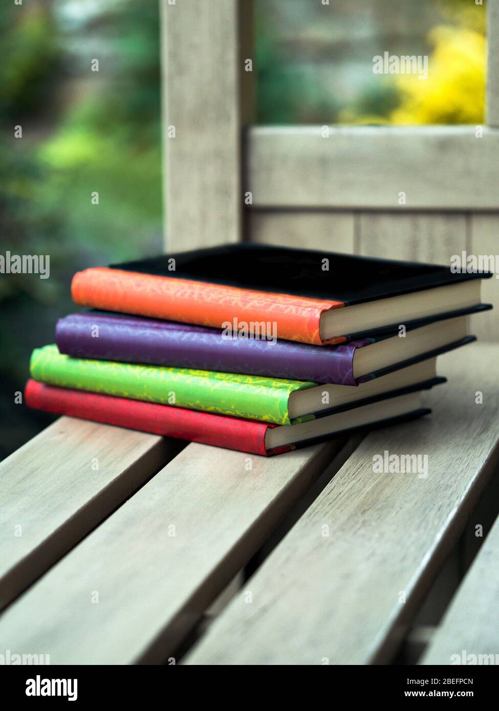 Hardbook books with coloured spines on bench in garden Stock Photo - Alamy