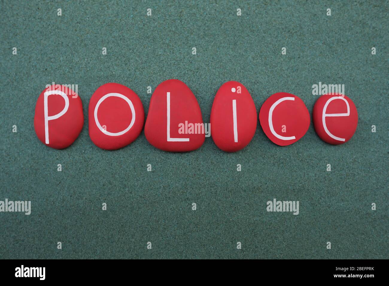Police word composed with red colored stone letters over green sand ...