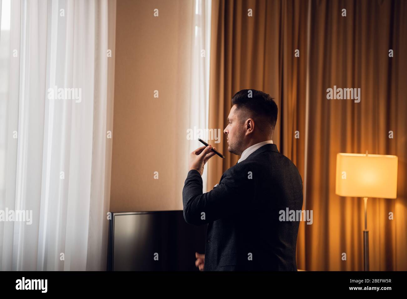 Side view of a handsome young businessman making a phone call, standing ...