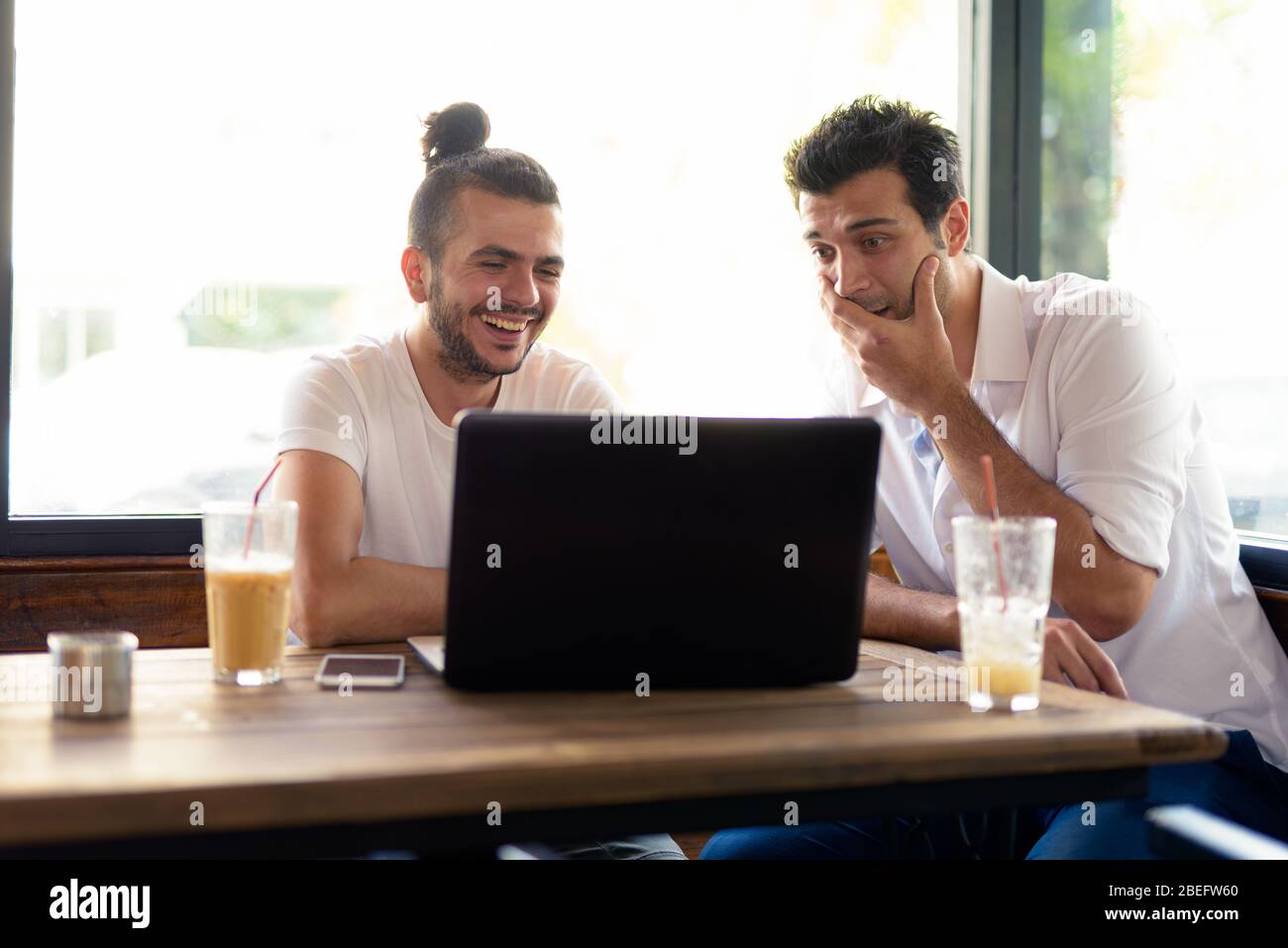 Two happy men as friends using laptop together at the coffee shop Stock ...