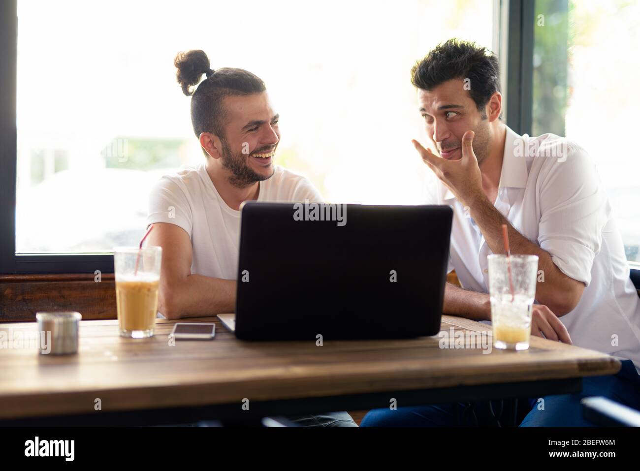 Two happy men as friends using laptop together at the coffee shop Stock ...