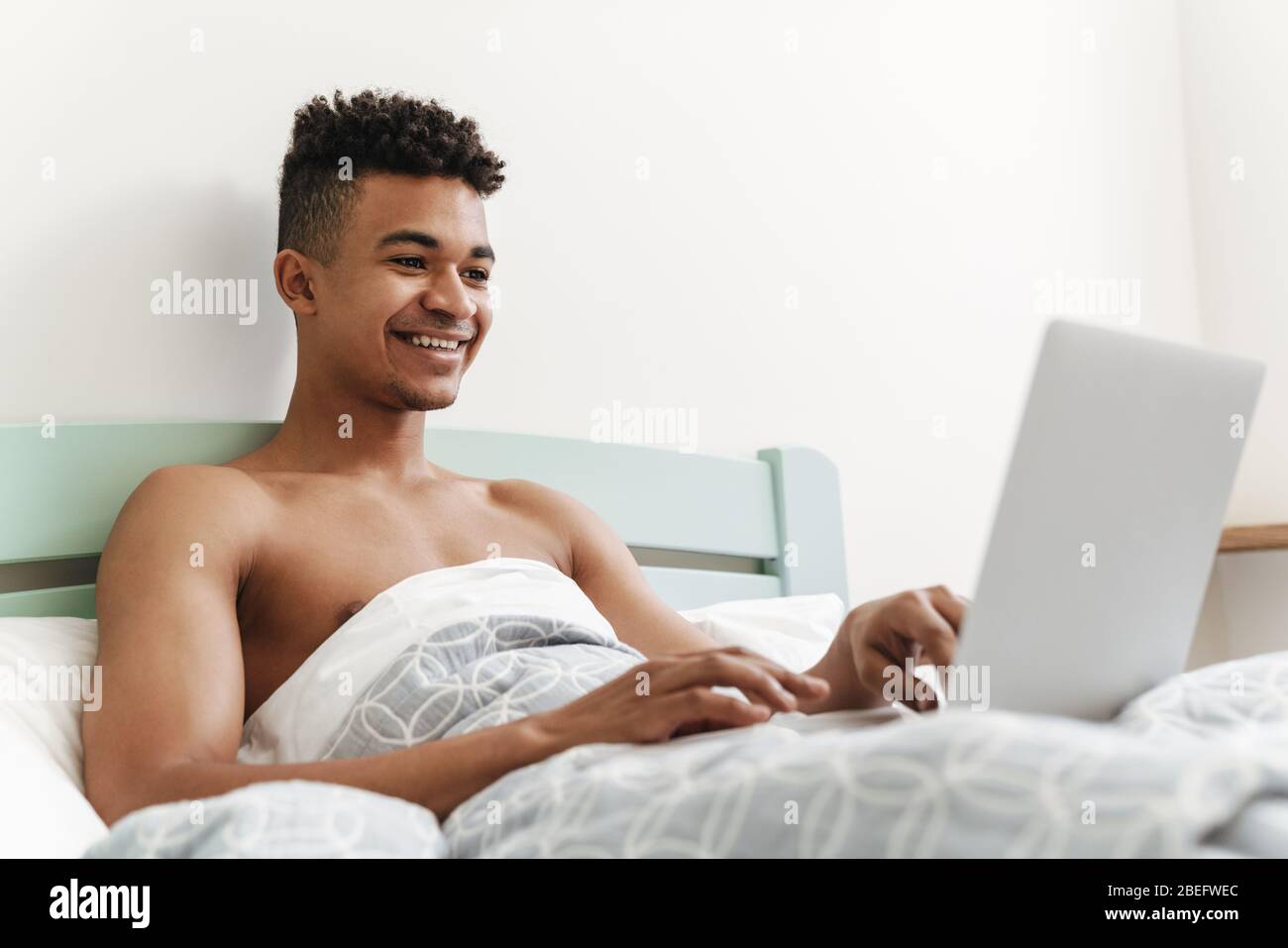 Photo of young happy positive african guy in the morning in bedroom ...