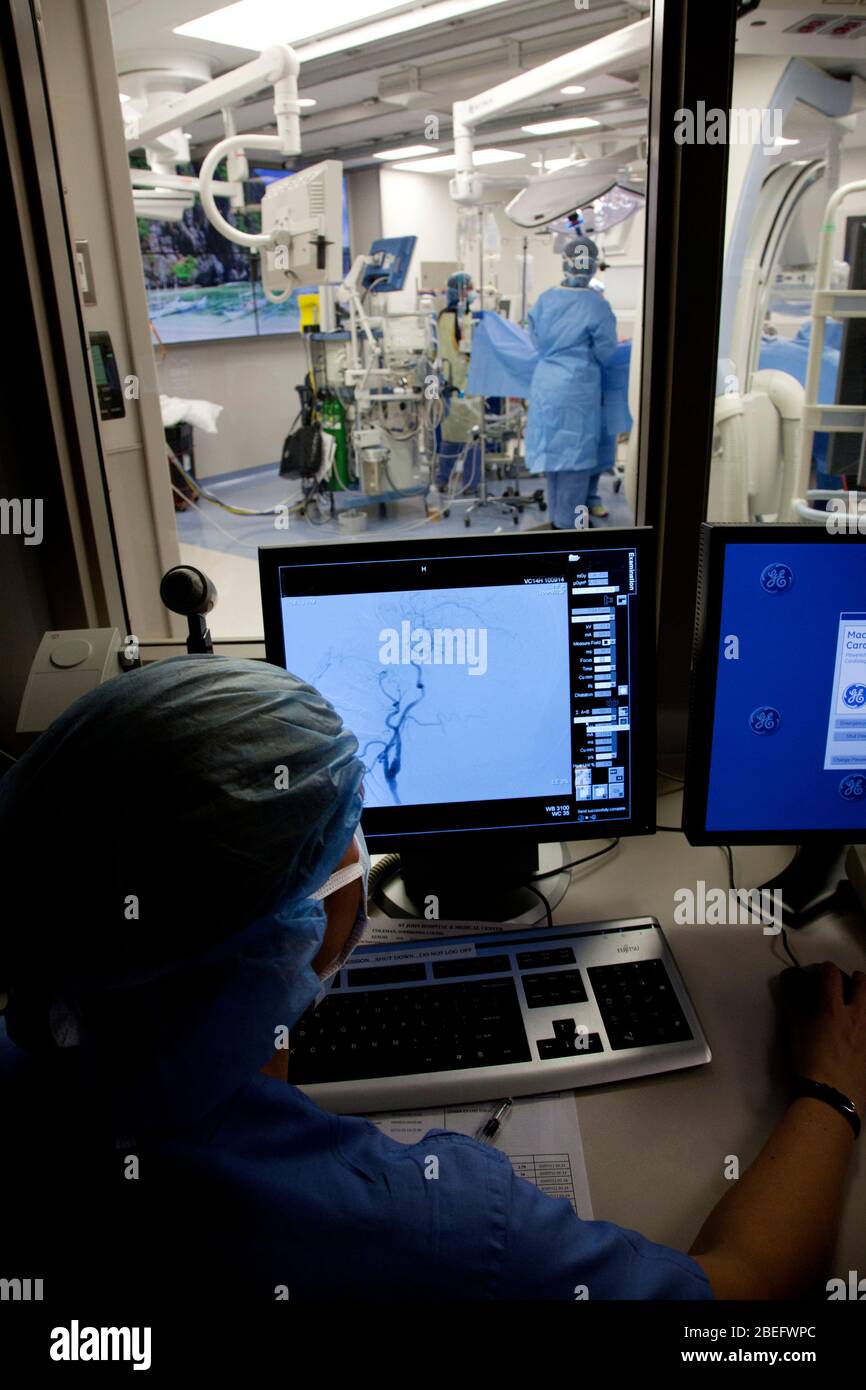 Technician examines scan of patient's blood vessels during operation to ...