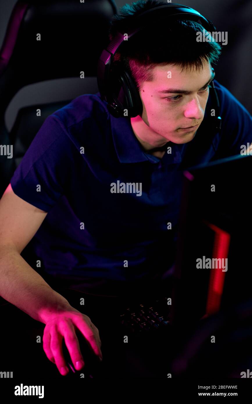 Addicted young male gamer in headset with microphone using computer ...