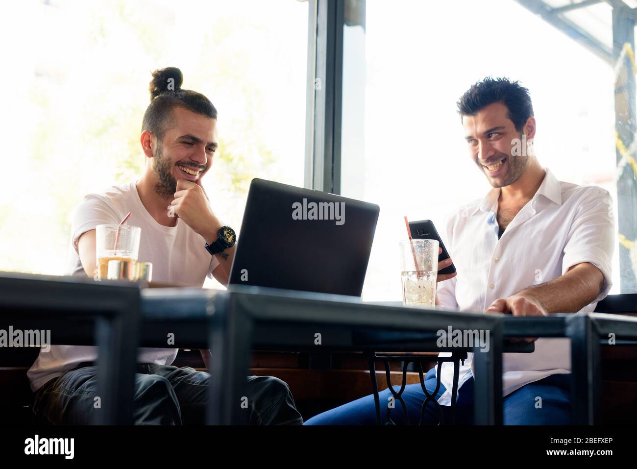 Two happy men as friends thinking and working together at the coffee ...