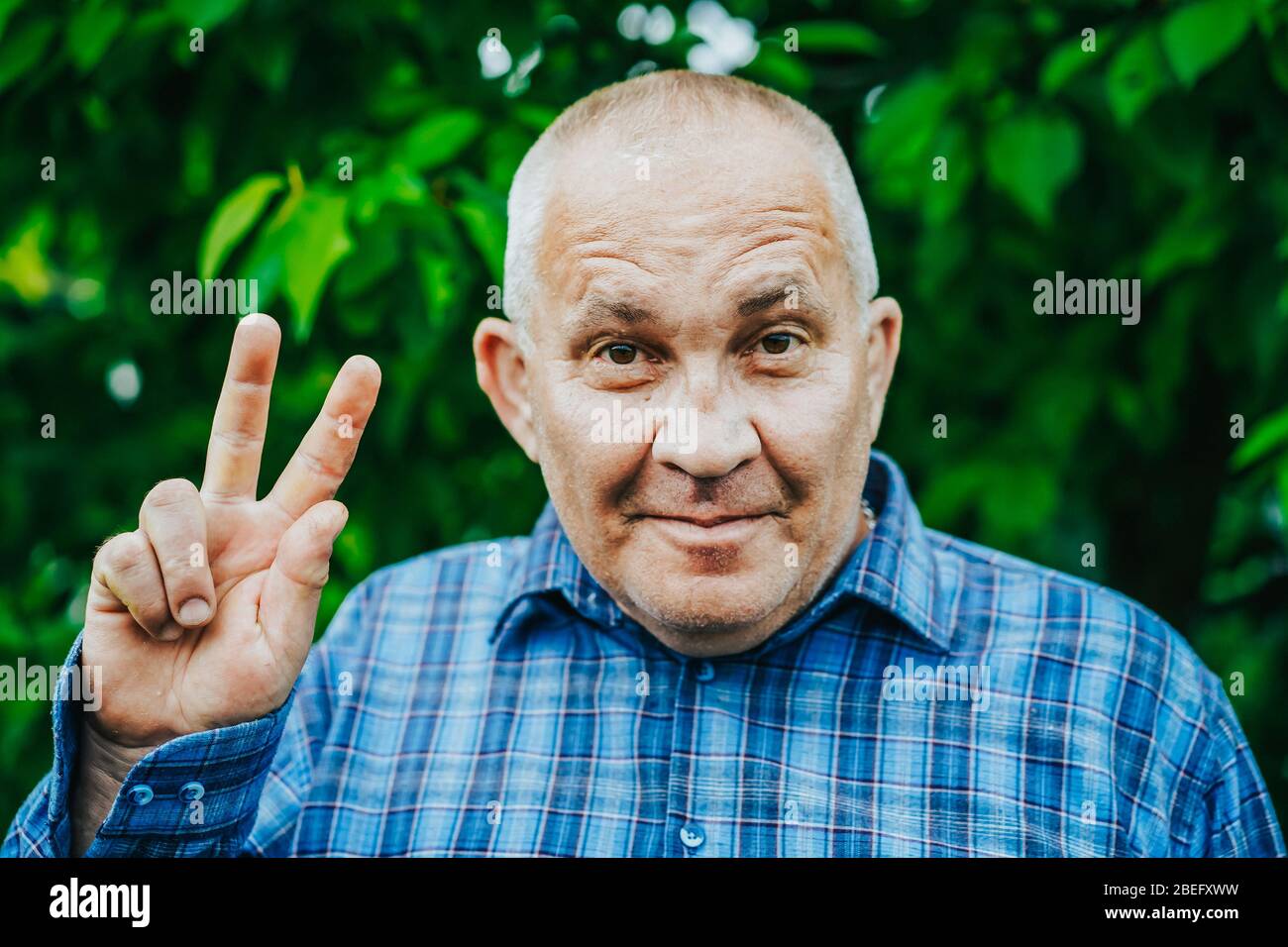 Aged boomer man making OK peace sign over green park background. Winner ...