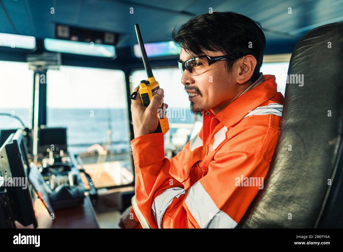 Filipino deck Officer on bridge of vessel or ship. He is speaking on ...